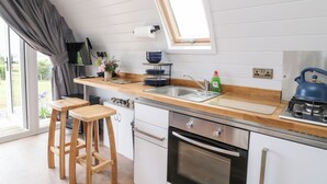 Cozinha moderna com bancada de madeira, forno embutido, pia e janela acima da pia.