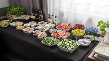 Uma mesa de buffet com diversos alimentos e acompanhamentos.