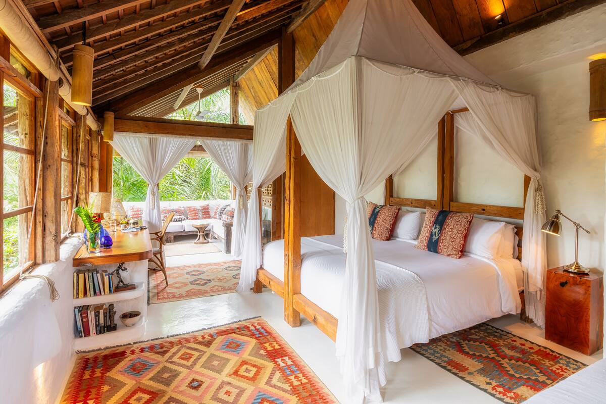Um quarto espaçoso com uma cama grande, uma cabeceira de madeira, uma mesinha de cabeceira e um criado-mudo.