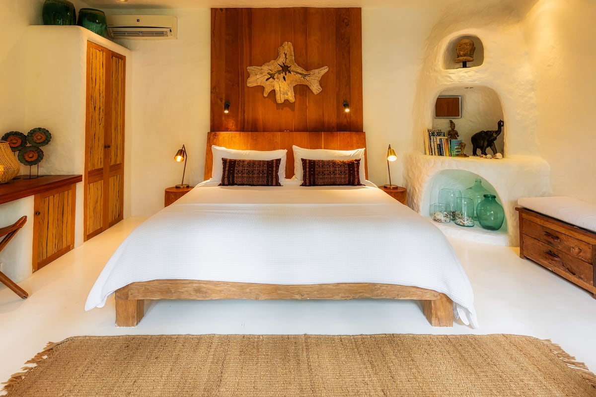 Quarto com uma cama grande, cabeceira de madeira e decoração rústica.