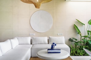 Uma sala de estar moderna com um sofá seccional, uma mesa de centro redonda e uma grande obra de arte na parede.