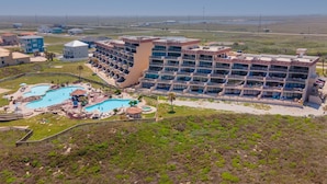 Um resort com vários edifícios, uma grande piscina e área de praia.