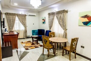 Uma sala de jantar com uma mesa redonda e cadeiras, um sofá e cortinas.