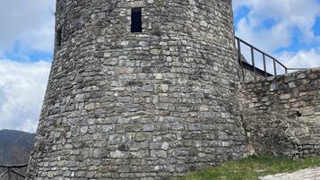 Uma torre de pedra com uma janela estreita e uma grade de metal.