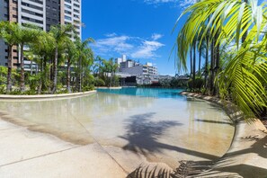 Piscina cercada por palmeiras e edifícios.