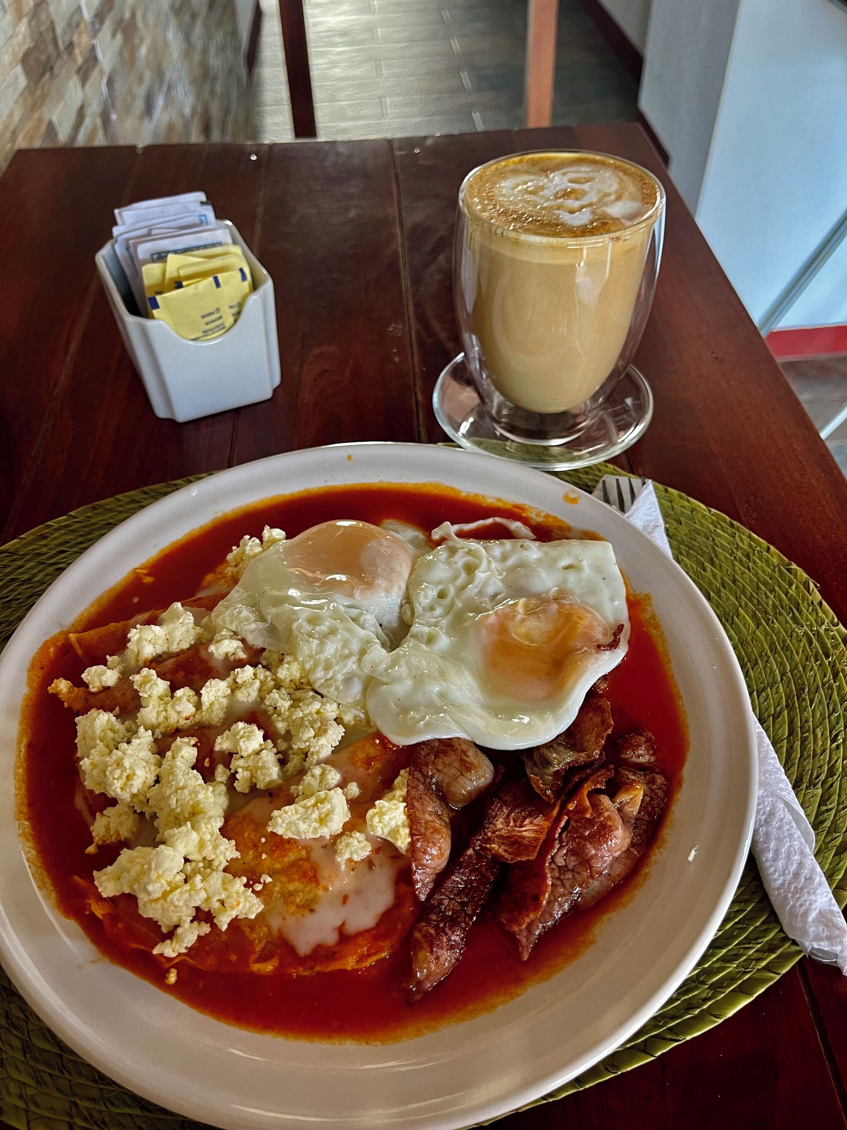 Um prato de comida com ovos, queijo e carne, e uma xícara de café sobre uma mesa.