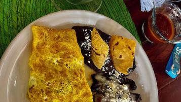 Um prato com uma omelete dobrada, uma xícara de café e uma pequena tigela de molho.