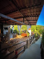 Um pátio externo com mobiliário de madeira, um espaço de bar e vista para vegetação exuberante.