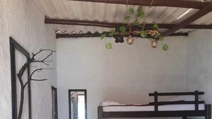 Quarto com beliche, manta xadrez, quadro de árvore enquadrada e luminária pendente.