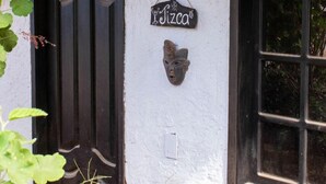 Um edifício rústico com uma porta preta e uma janela. Uma placa na parede diz 'Pizza'.
