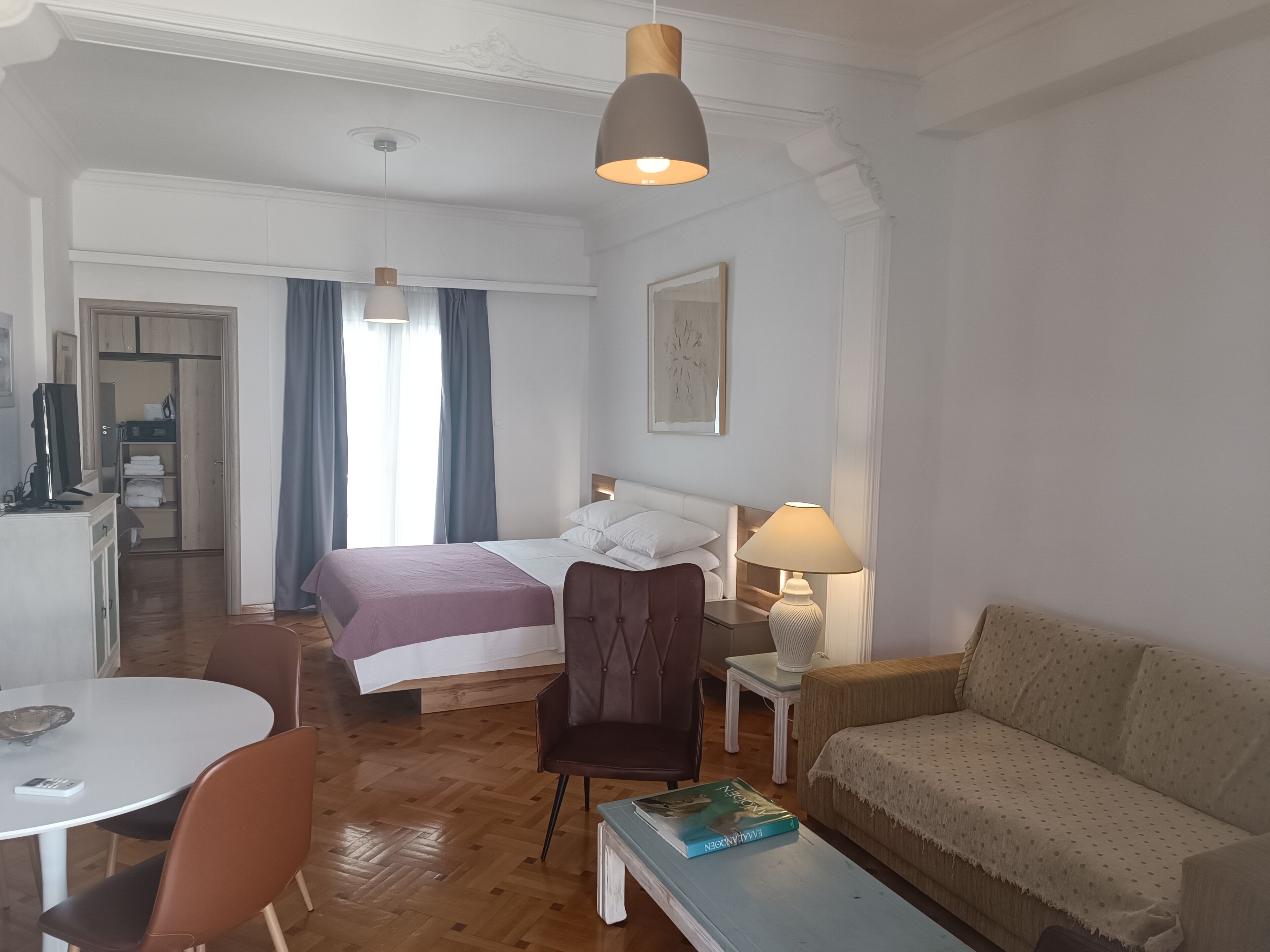 Quarto de hotel com cama, escrivaninha, cadeira, sofá e luminária.