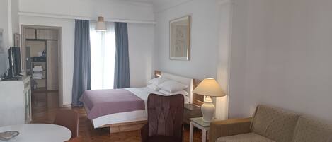 Quarto de hotel com cama, escrivaninha, cadeira, sofá e luminária.