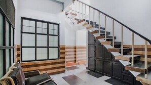 Um quarto com escada, janela e um espaço de estar com cadeiras.