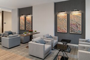 Uma sala de estar moderna com sofás cinzas, uma mesa de centro e arte abstrata nas paredes.