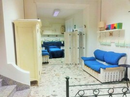 Quarto com uma cama, um sofá azul, um guarda-roupa e uma pequena mesa com abajur.
