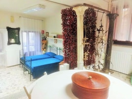 Um quarto com uma cama, uma mesa com um objeto vermelho e uma coluna decorada com hera.