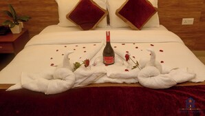 Cama arrumada com garrafa de champanhe, pétalas de rosa e toalhas em forma de cisne.