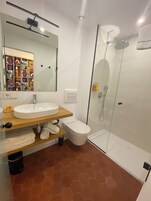 Um banheiro moderno com pia branca, vaso sanitário e chuveiro com divisória de vidro.