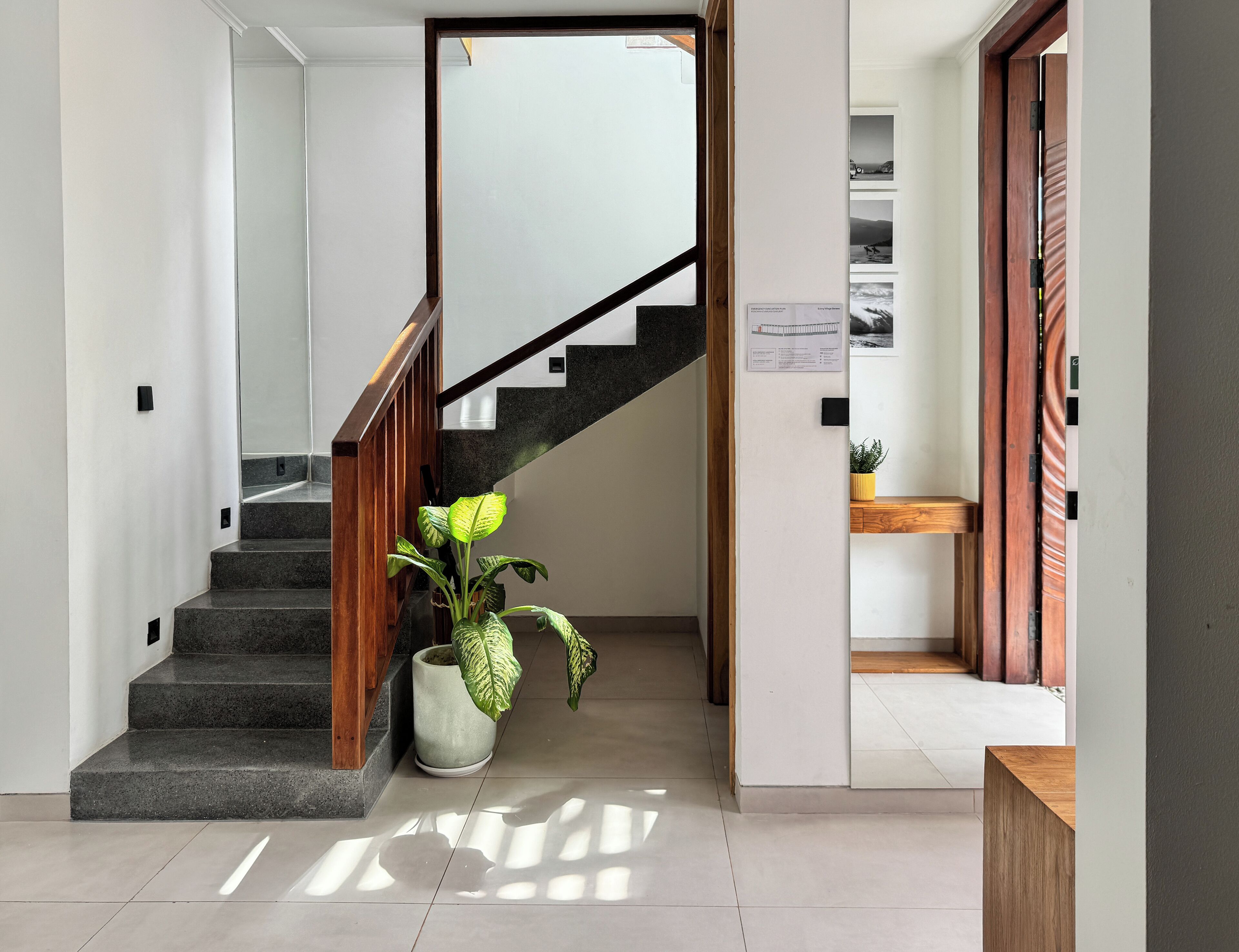 Uma escadaria com corrimão de madeira e um vaso de planta na base.