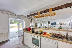Cozinha moderna com teto de vigas de madeira, forno embutido e pia com adega acima.