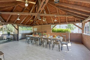 Uma sala de jantar ampla com teto de madeira alto, várias luminárias pendentes e uma mesa comprida posta para refeições.