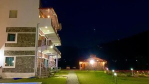 Um hotel moderno com piscina, gramado bem cuidado e céu noturno limpo.