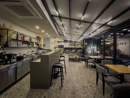 Um café moderno com área de bar, mesas e vista através de grandes janelas.
