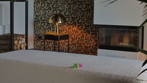 Quarto com parede estampada, lareira e uma mesa com objeto decorativo.