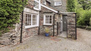 Uma casa de pedra com varanda coberta e um pequeno jardim.