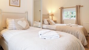 Quarto de hotel com duas camas, um espelho grande, uma janela com cortinas e um quadro na parede.