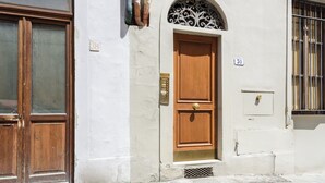 Um edifício com porta de madeira, um portão de metal e uma placa com o número 30.
