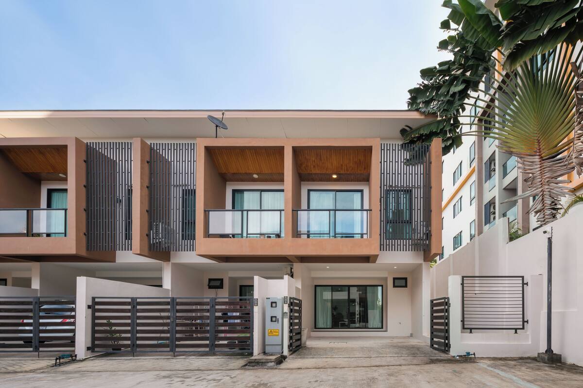 Um edifício moderno de vários andares, com varandas, janelas amplas e portão fechado.