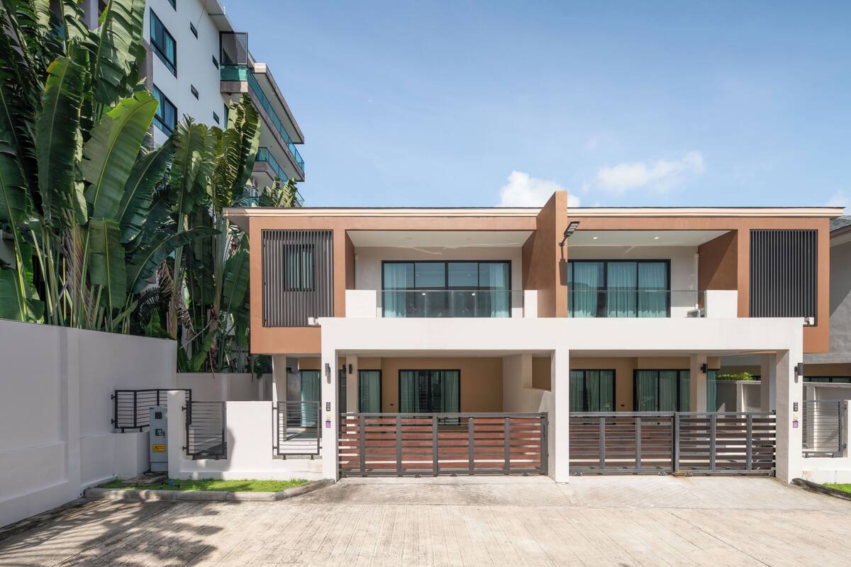 Uma casa moderna de dois andares com garagem coberta, janelas amplas e portão fechado.