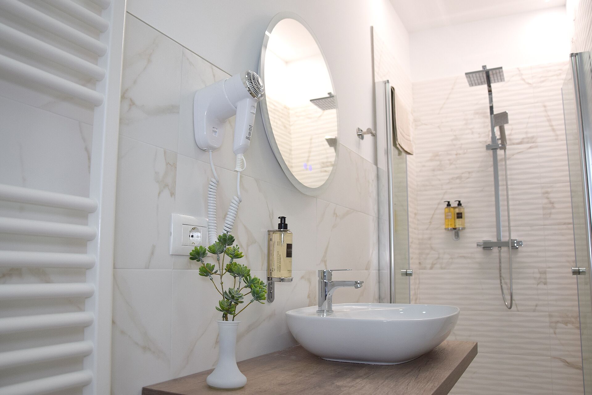 Casa de banho com lavatório branco, secador de cabelo, espelho e zona de chuveiro.