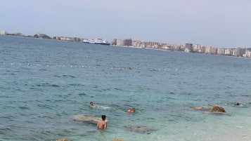 Uma praia privada, praia de areia branca, guarda-sóis de praia