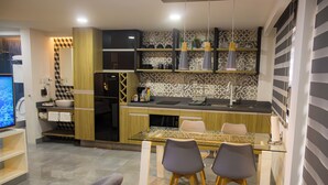 Uma cozinha moderna com mesa de jantar de vidro, cadeiras cinzas e eletrodomésticos embutidos.