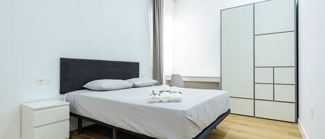 Quarto com cama, mesa de cabeceira e guarda-roupa.