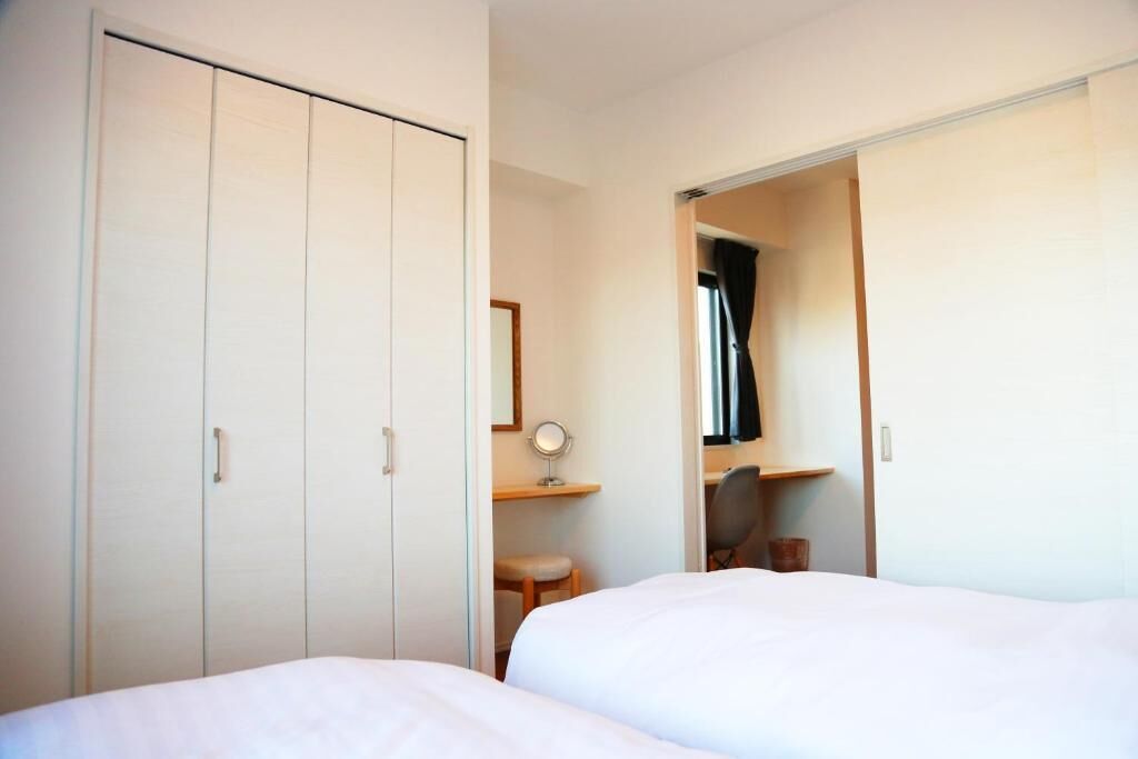 Quarto de hotel com cama, guarda-roupa, escrivaninha e espelho.