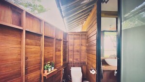 Uma casa de banho em madeira com sanita, lavatório e zona de duche.