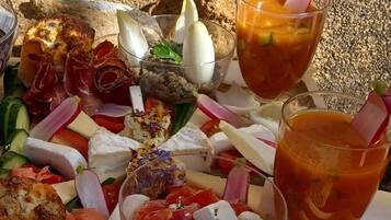 Diversos alimentos, incluindo queijo, embutidos e um copo de chá gelado, dispostos sobre uma tábua de madeira.