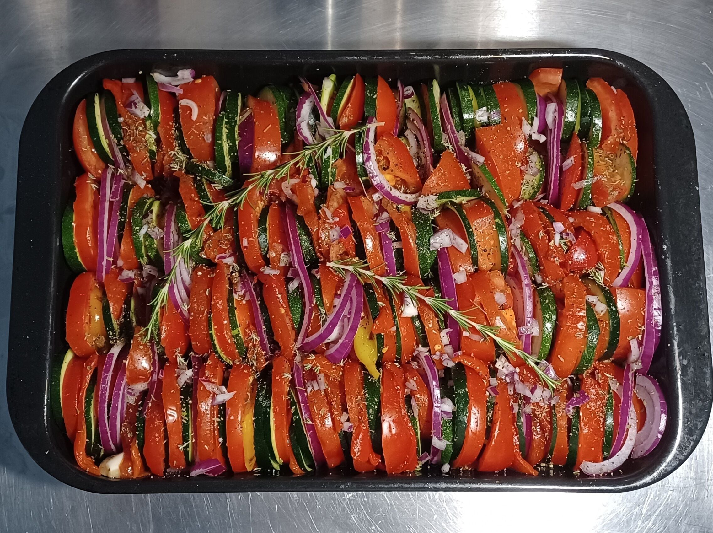 Uma travessa com legumes fatiados, incluindo tomates, pepinos e cebolas roxas.