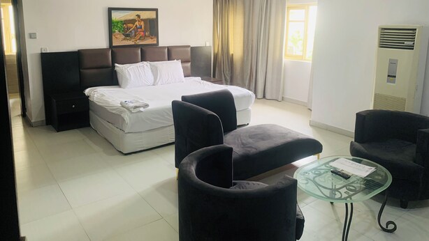 Quarto de hotel com uma cama grande, uma mesa pequena com um controle remoto e uma cadeira.