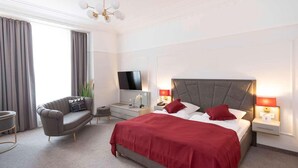 Quarto de hotel moderno com uma cama grande, televisão, escrivaninha e uma cadeira.
