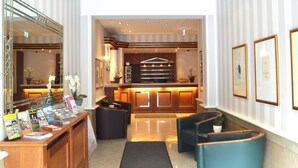Um saguão de hotel com balcão de recepção, área de estar e vista para a sala de jantar.