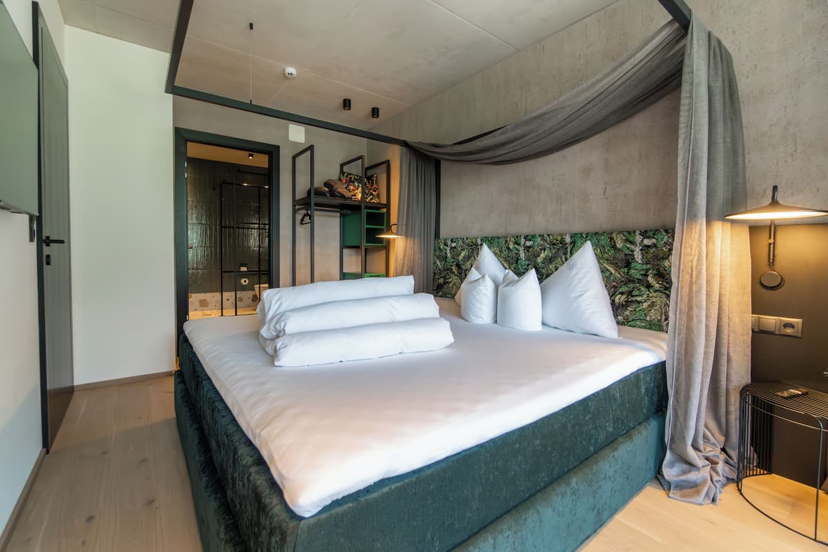 Quarto moderno com uma cama grande, cabeceira com painel verde texturizado e luminária de cabeceira.