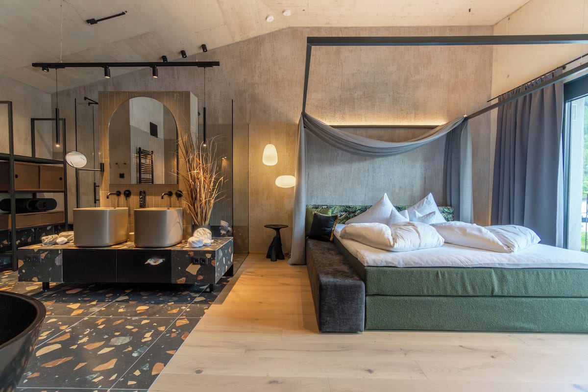 Quarto de hotel moderno com uma cama grande, uma toucador com espelho e um espaço de estar.