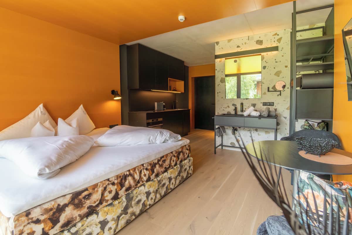 Quarto moderno com cama, escrivaninha e banheiro.