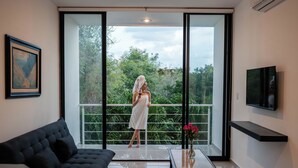 Uma sala de estar moderna com uma grande porta de vidro deslizante que dá para uma varanda com vista para o verde.