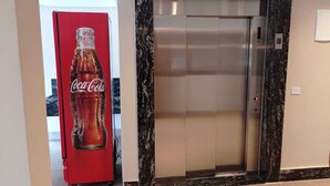 Um elevador com uma geladeira Coca-Cola ao lado.