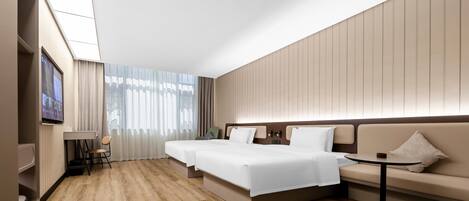 Quarto de hotel moderno com uma cama grande, um sofá, uma mesa pequena e uma televisão.